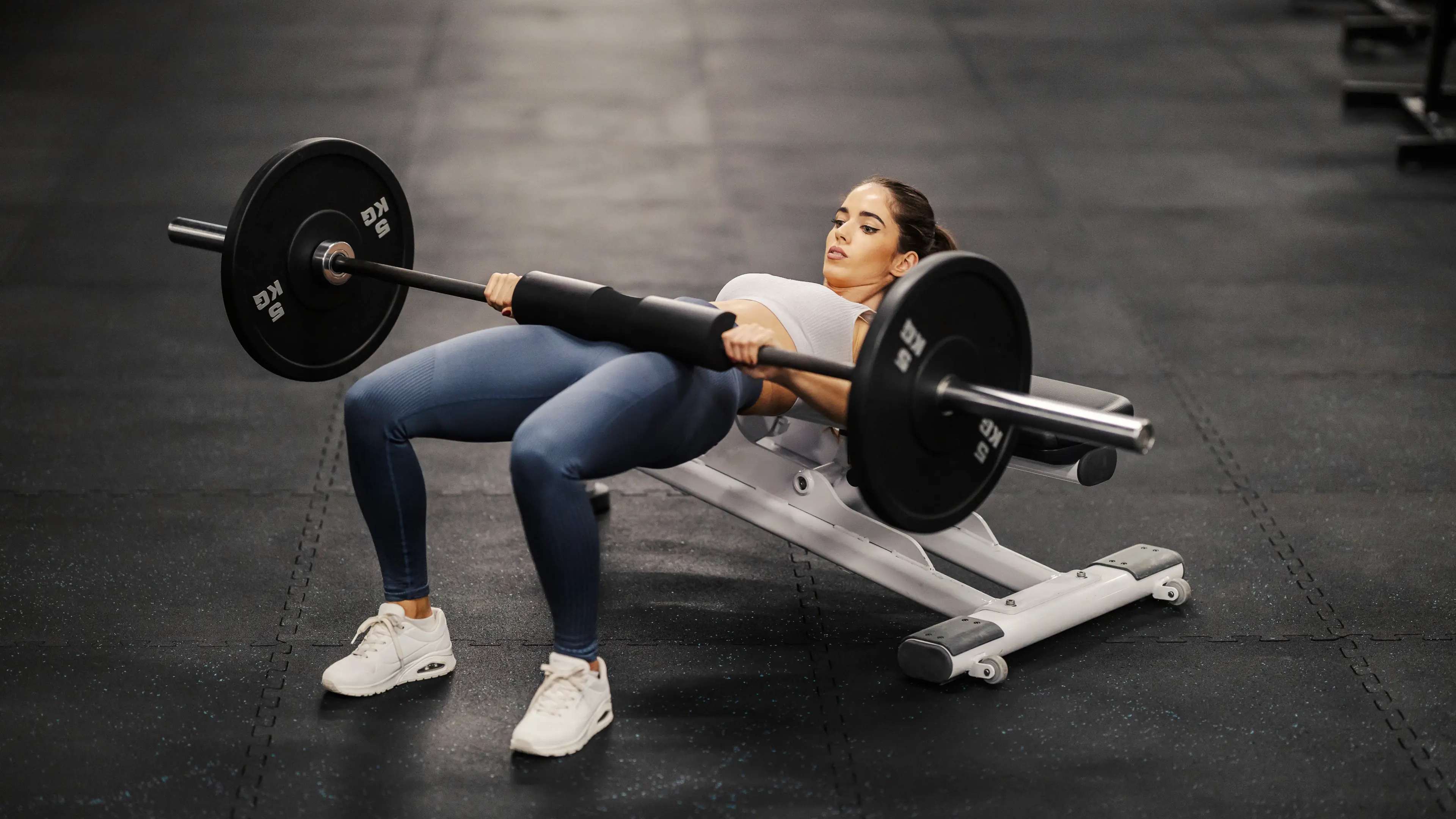 Eine Frau trainiert mit einer Langhantel Hip Thrusts